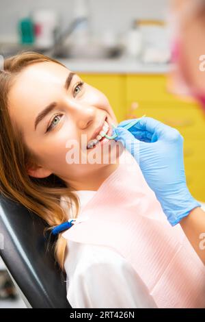 Female dentist with tool and plastic tooth on purple background. World ...