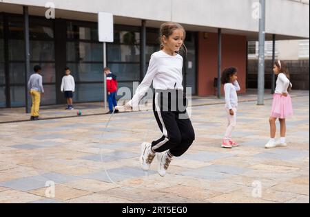 Sporty tween girl jumping rope in school yard during recess Stock Photo ...