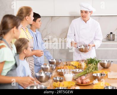 Young chef giving culinary classes to group of interested tweens Stock ...