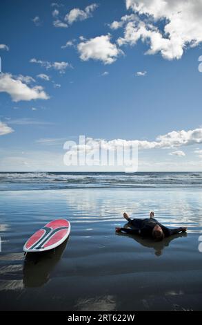 Exhausted man lying on sand after intense workout session. Athlete ...