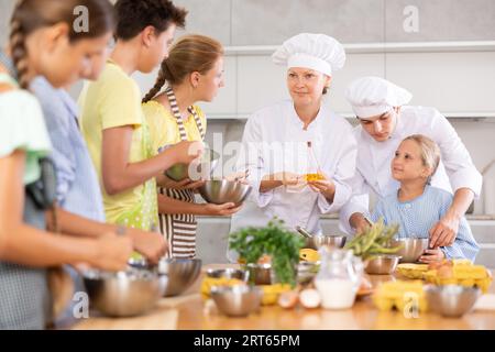 Two friendly chefs giving culinary lesson to group of tweens Stock ...