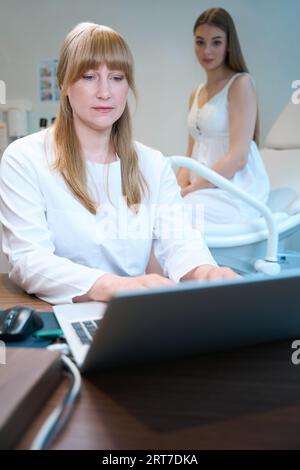 a young woman gynecologist at the workplace with a laptop and an ...