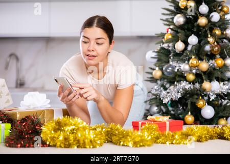Focused casual young female searching info on smartphone near packed ...