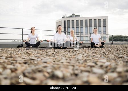 Female yoga practitioners holding lotus position outdoors Stock Photo ...