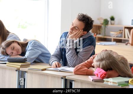 Tired sleepy classmates sitting at desks in classroom Stock Photo - Alamy