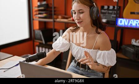 Young woman radio reporter opening laptop wearing headphones speaking ...