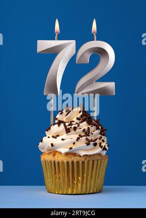 Birthday number 72 - Candle lit on blue background Stock Photo - Alamy