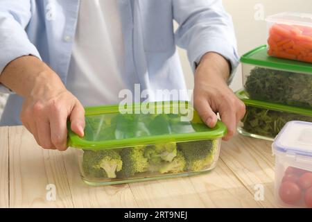 Man closing glass container with lid at light grey marble table in ...