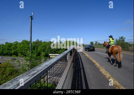 Car passing horse and rider on a road bridge crossing the M40 motorway ...