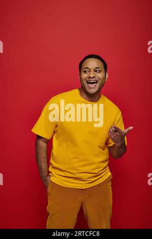 gleeful indian man in bright casual clothes looking away and smiling on ...