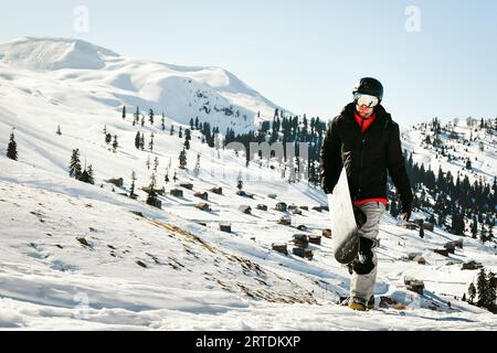 man walking by hill with snowboard mountains on background Stock Photo ...