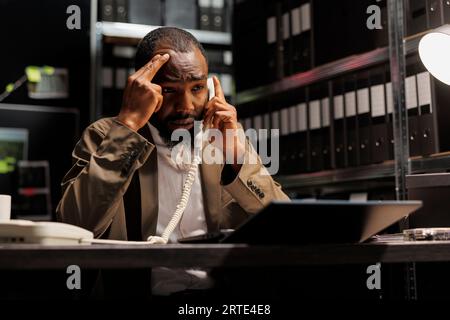 African american police investigator answering landline phone call in ...