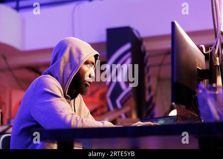 African american internet thief planning phishing attack and online scam in hideout workspace ...