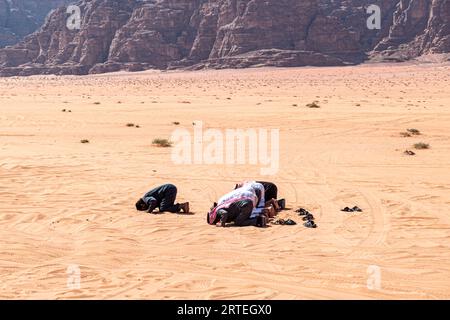 Bedouin men bowing down for muslim prayer in the middle of Wadi Rum ...