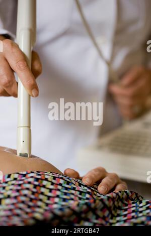 Female doctor performing ultrasound of belly of pregnant woman in ...