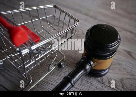 Closeup image of judge gavel and shopping trolley on table. Consumer ...