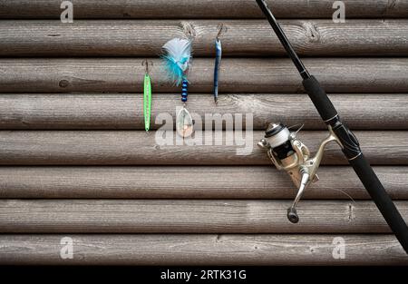 spinning wheel and rod with coourful lures hanging on a grey wall of ...