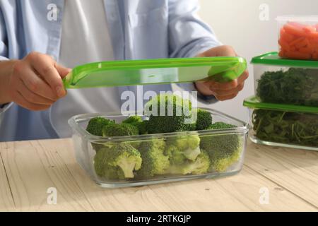 Man closing glass container with lid at light grey marble table in ...