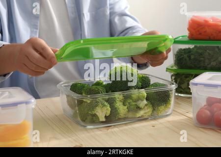 Man closing glass container with lid at light grey marble table in ...