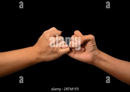 Two hands hooking each other little finger on black background, symbol ...