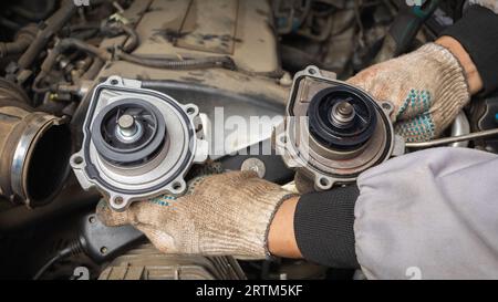 An auto mechanic holds a new and old car engine pump in his hands Stock ...
