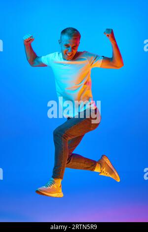 Neon light portrait of victorious delighted happy man raising hands ...