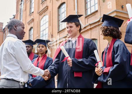 Shaking hands, graduation and certificate for college student with ...