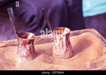 Closeup of cezves with hot coffee on a tray on the table with water ...