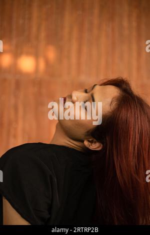 an Asian man sleeping on a brown table with long hair hanging down ...