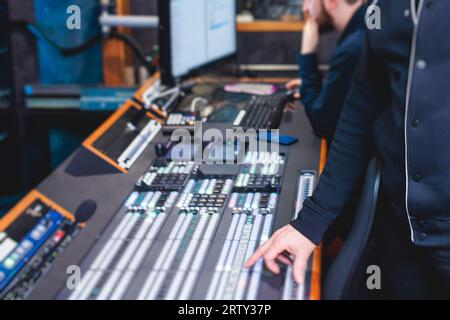 View of lighting technician operator working on mixing console ...