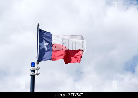 Texas state flag flying against a blue sky and white cloud background ...