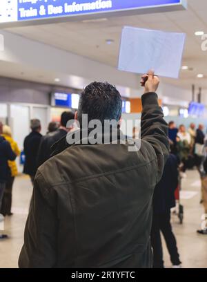 Greeting driver holding passenger name card in Arrivals at Heathrow's ...