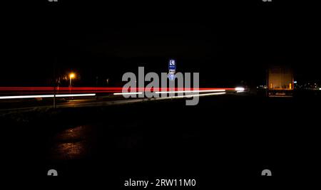 Cars passing an emergency stop sign at night on a busy highway Stock ...