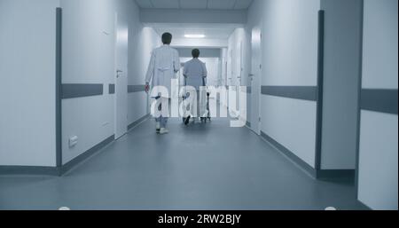 Transfer to ward. View of a female doctor (centre right) supervising ...
