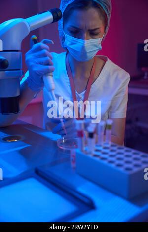 Laboratory employee works with a powerful microscope at the workplace ...