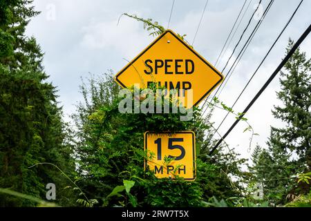 Traffic signs overgrown with plant vines, speed bump and 15 MPH ...