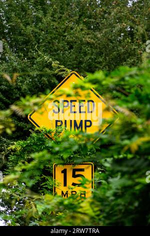 Traffic signs overgrown with plant vines, speed bump and 15 MPH ...