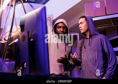Men in hood discussing hacking plan with cheerful smile in abandoned ...