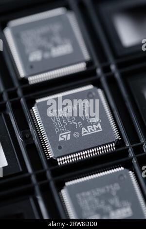 ARM logo seen on STM32 microchip hold in tweezers and blurred ARM ...