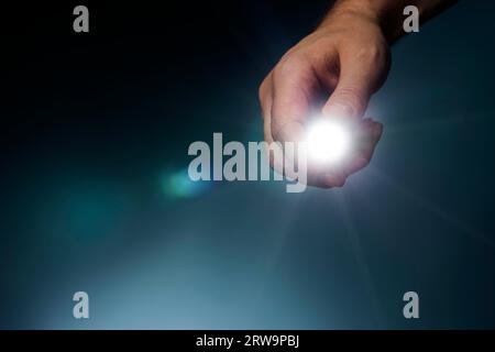 person pointing flashlight beam towards aurora borealis on winter night ...