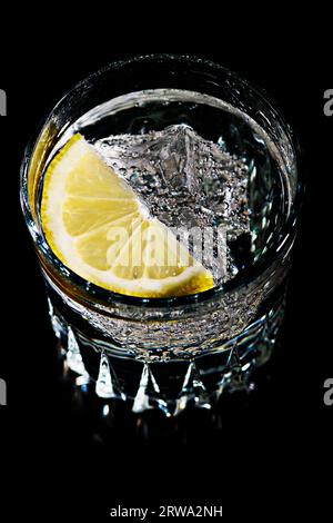 A glass of mineral water photographed from above on a black background. The glass contains water ...