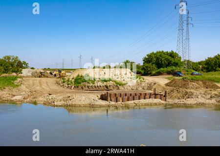 Installed metal piles along river bank, build in for bridge foundation ...