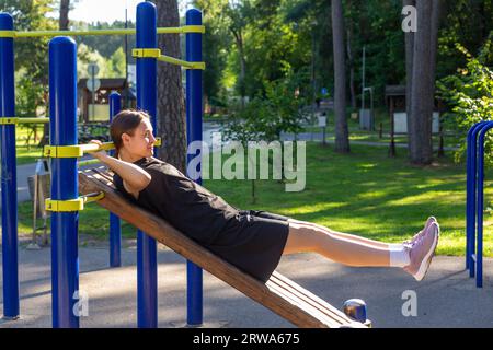 A teenage girl doing abdominal crunches. A girl performs exercises for ...
