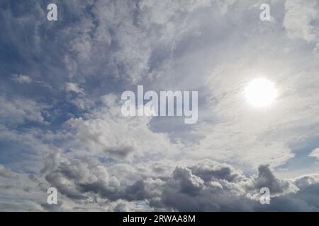 blue sky with sun and mixed clouds on different layers, above horizon ...