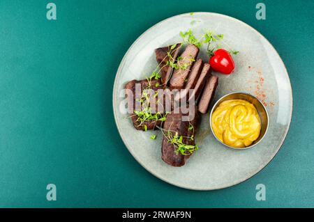 Roasted ostrich steaks with sauce on a plate. African food. Space for ...