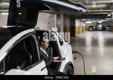 Professional operating computer in EV on charge in garage Stock Photo ...
