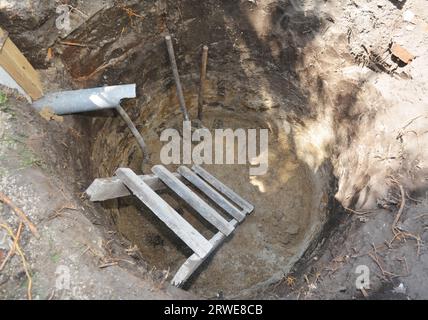 Digging a deep round hole with sewer line, drain pipe outlet for a ...