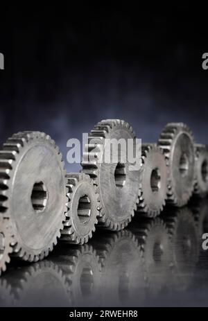 A row of old metallic cog gears being filled with one blurry falling ...