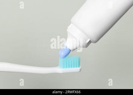 Applying paste on toothbrush against grey background Stock Photo - Alamy