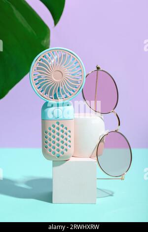 Plaster podium with portable electric fan, monstera leaf and stylish ...